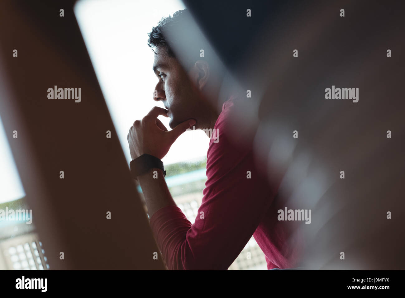 Thoughtful man looking through window at home Stock Photo - Alamy