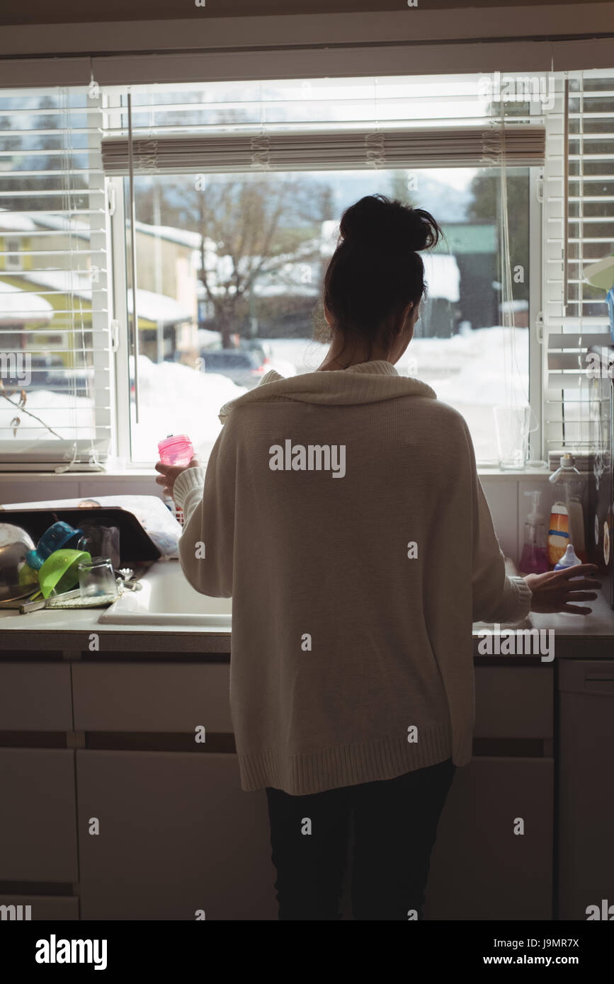 Rear view of woman standing near the kitchen sink at home Stock Photo ...