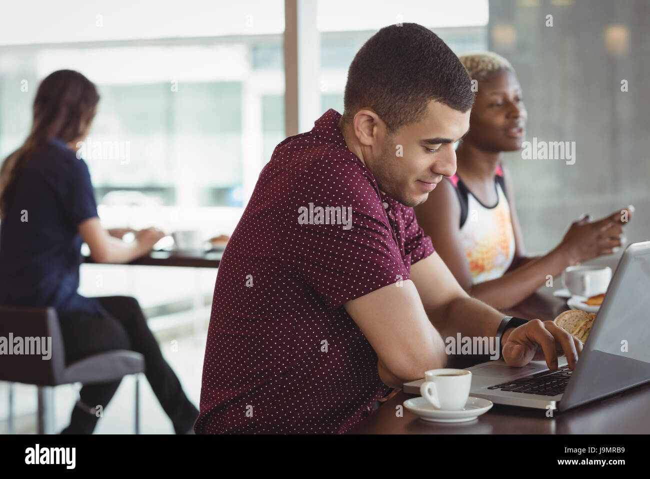 Male executive using laptop in office cafeteria Stock Photo - Alamy