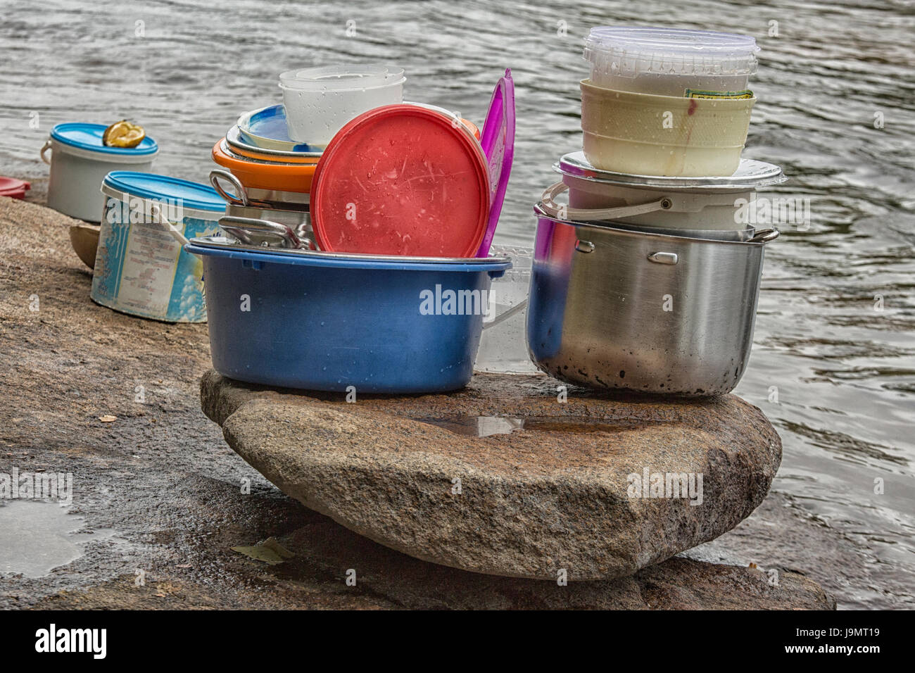 Stack of just cleaned plastic containers, plates and pans on a rock ...