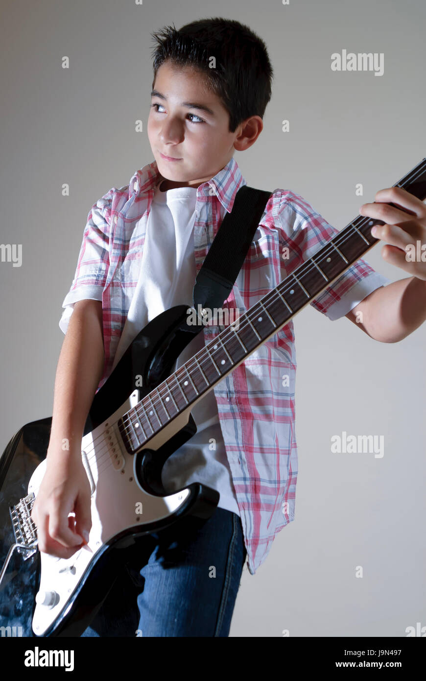Teen boy playing an electric guitar, capturing a moment of musical ...