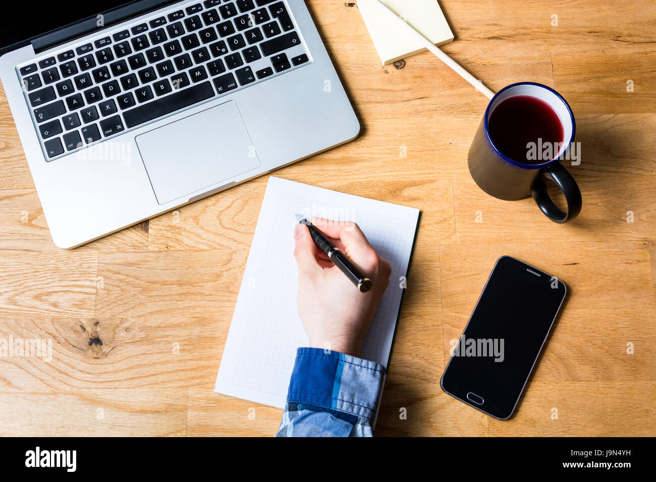 Taking business notes on work desk with laptop, smartphone and other ...