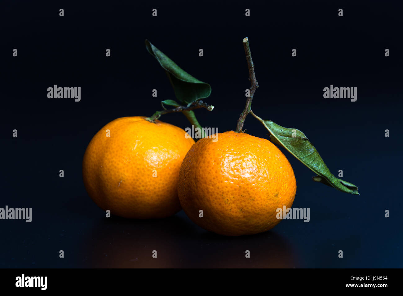 Two mandarins on black background Stock Photo - Alamy