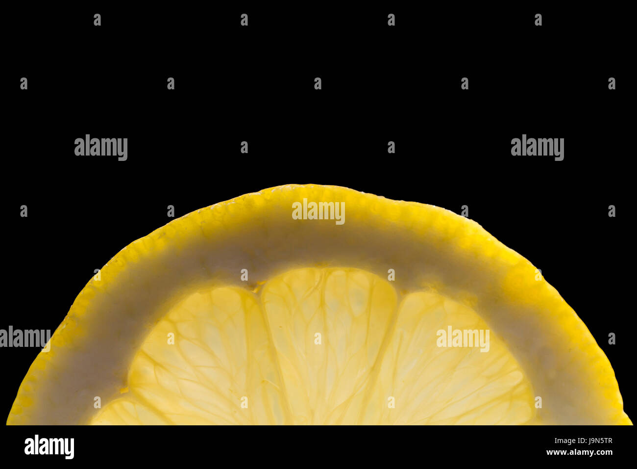 Backlit lemon slice on a black background Stock Photo - Alamy
