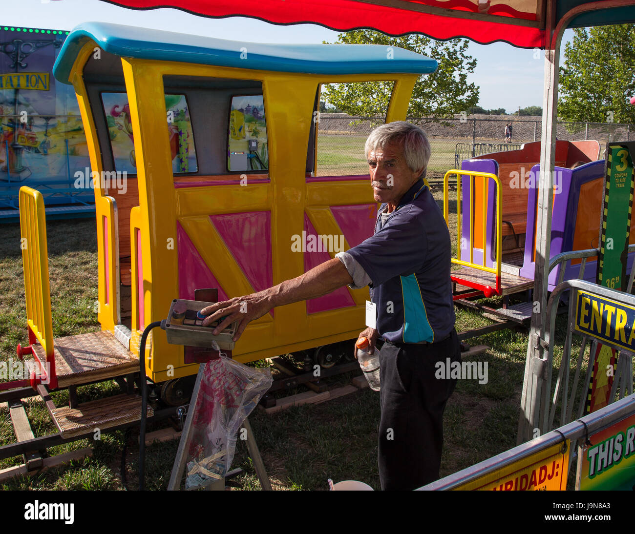 Proud carnival worker operating a train ride at the carnival Stock ...