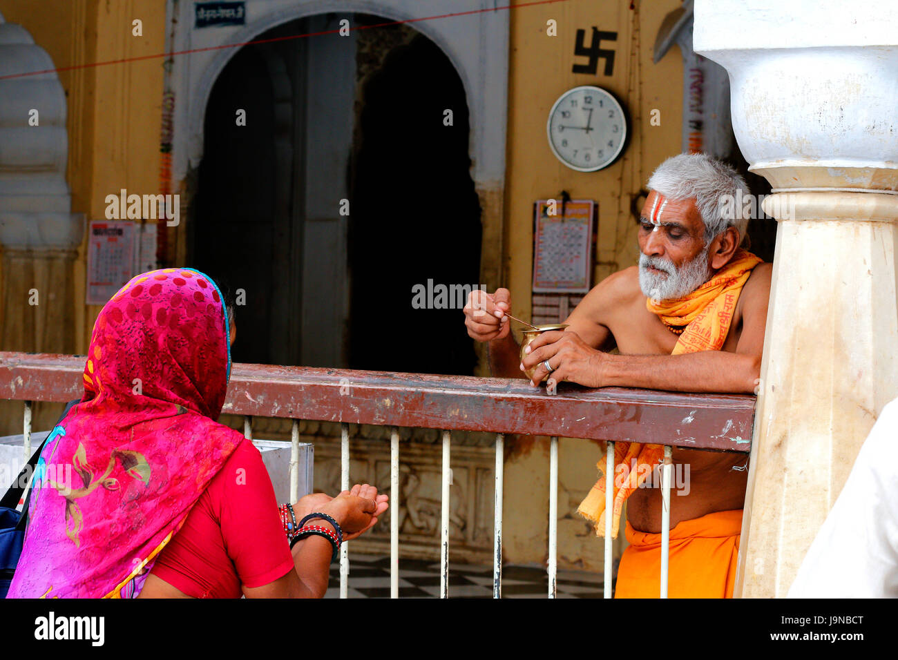 A hindu women devotee receiving prashad (blessings) from sadhu old ...