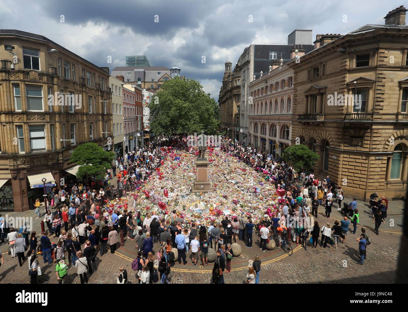 People look at flowers and tributes left in St Ann's Square in ...
