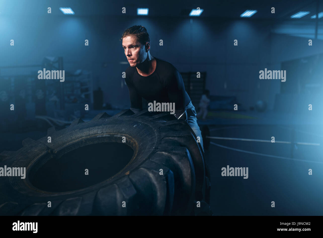 Male athlete on training, workout with heavy tire in gym. Energy ...