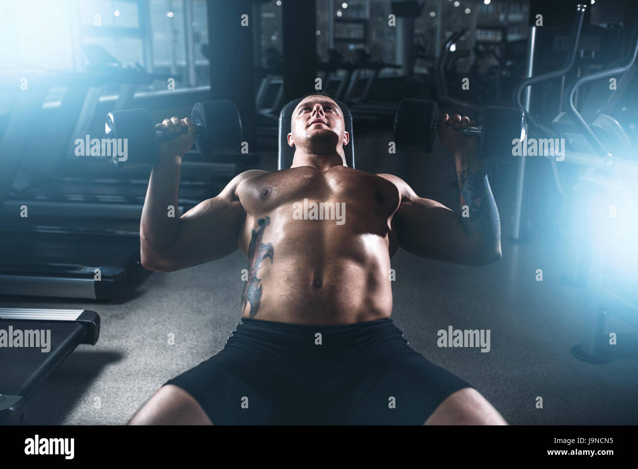 Muscular male bodybuilder training with dumbbells in sport gym ...