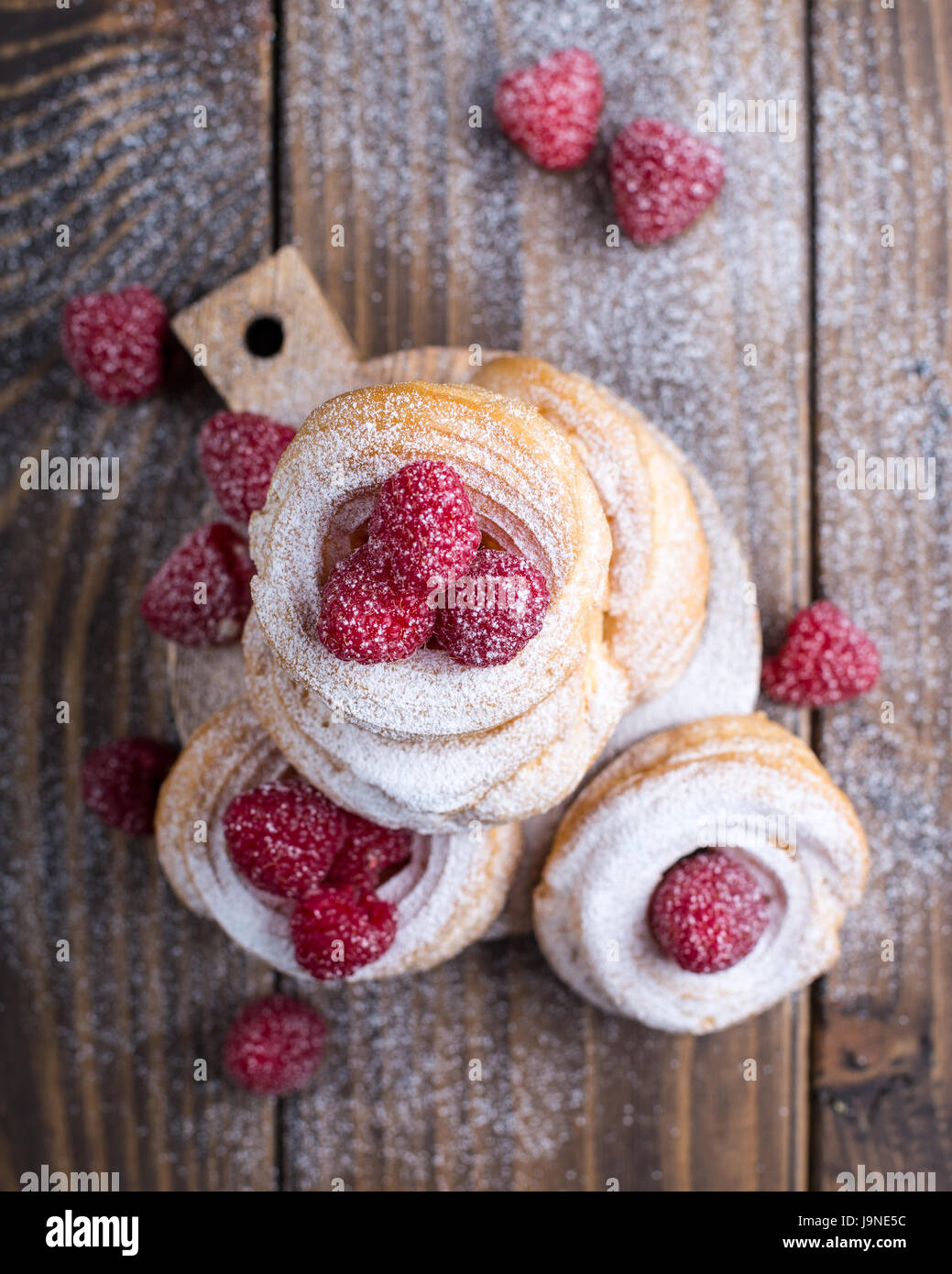 Round eclairs with raspberry decorated with powdered sugar Stock Photo ...