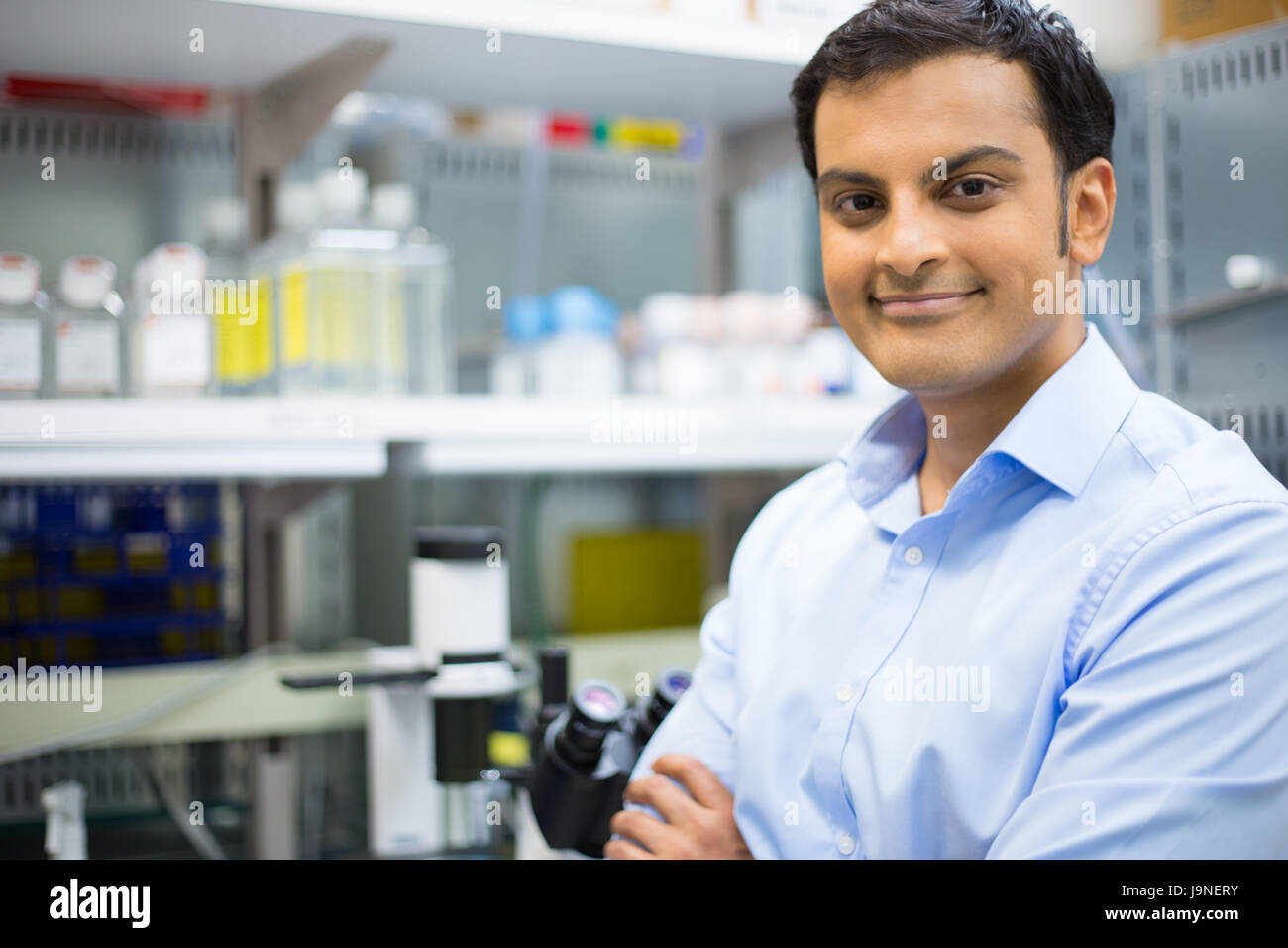 Closeup portrait, young friendly scientist standing by microscope ...