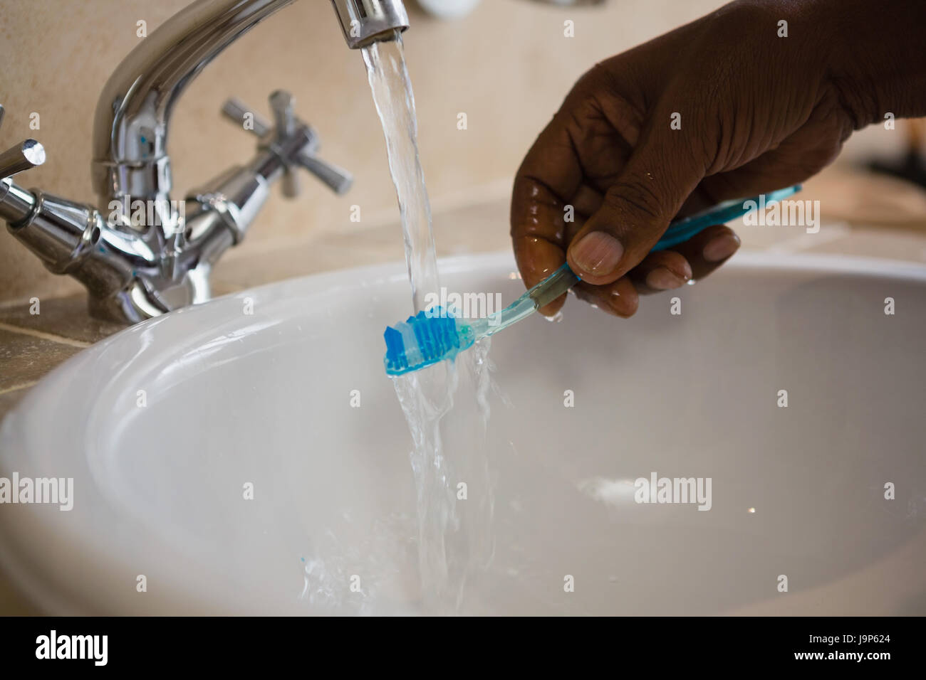 Cropped hand on man washing toothbrush in bathroom sink at home Stock ...