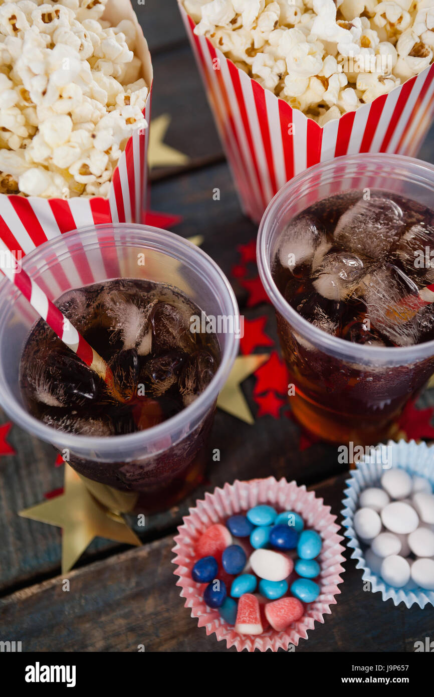 Popcorn, confectionery and drink arranged on wooden table Stock Photo ...
