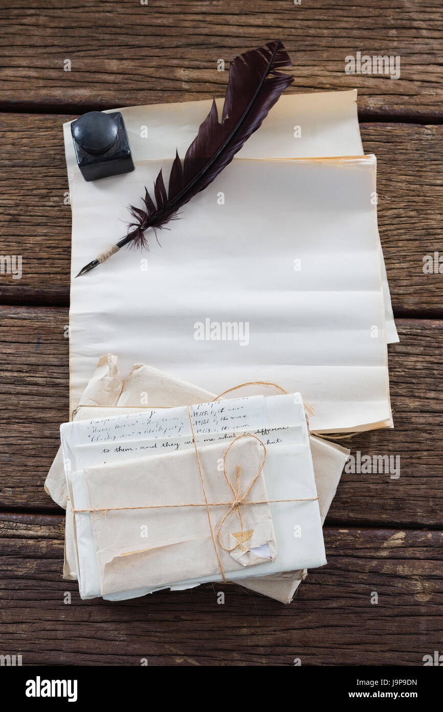 Quill feather, ink bottle and legal documents arranged on wooden table ...