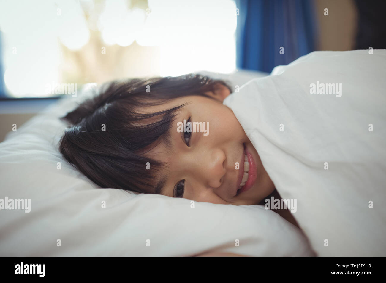 Portrait of smiling girl lying on the bed in bed room at home Stock ...