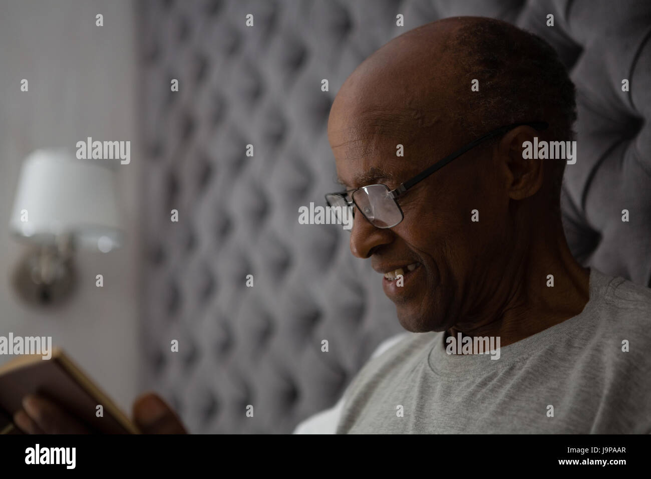 Smiling senior man reading book while resting on bed at home Stock ...