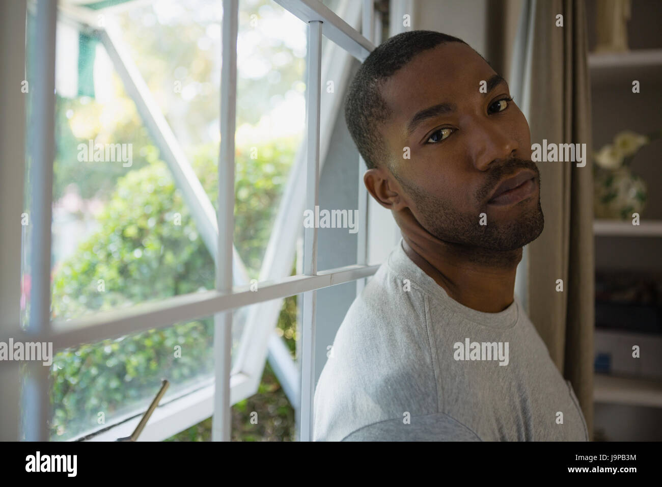 Portrait of man leaning on window at home Stock Photo - Alamy
