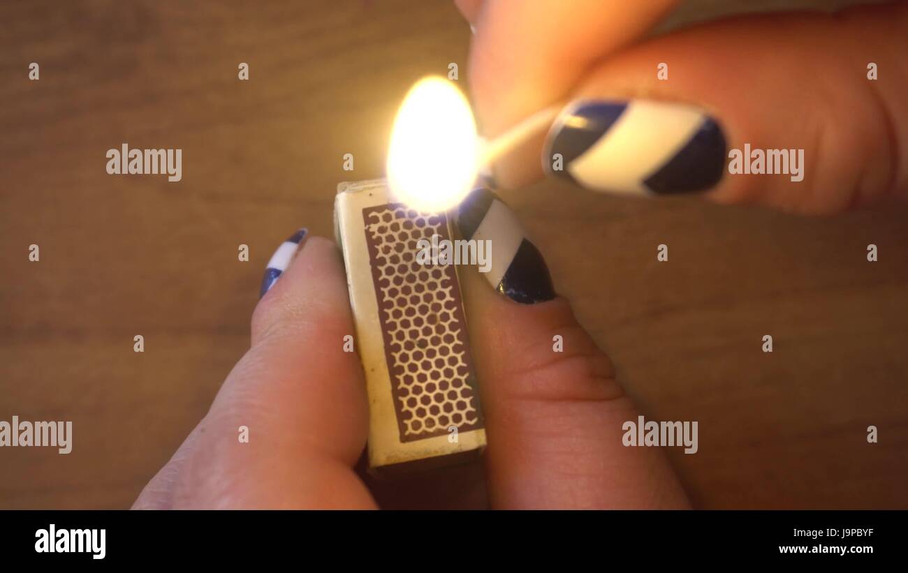 female hand lighting a match on a matchbox Stock Photo - Alamy