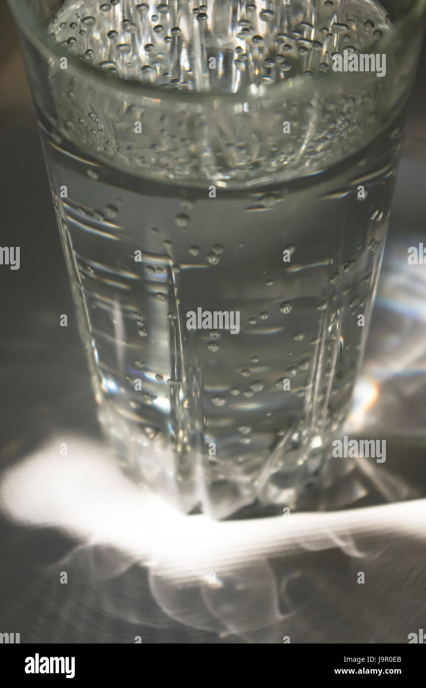 transparent faceted glass with bubbly water in the sun refracted light ...