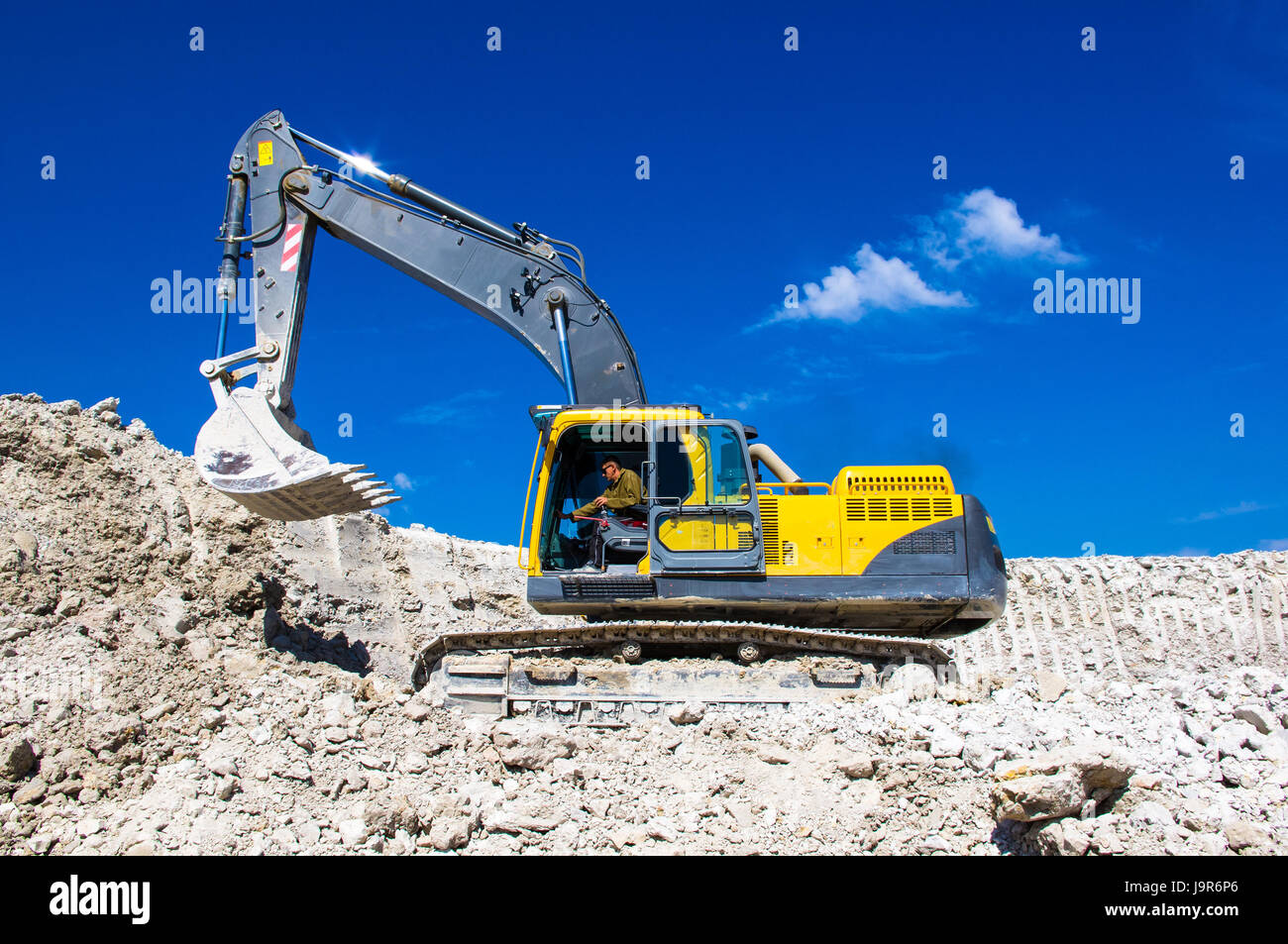 the excavator digging clay on blue sky background Stock Photo - Alamy