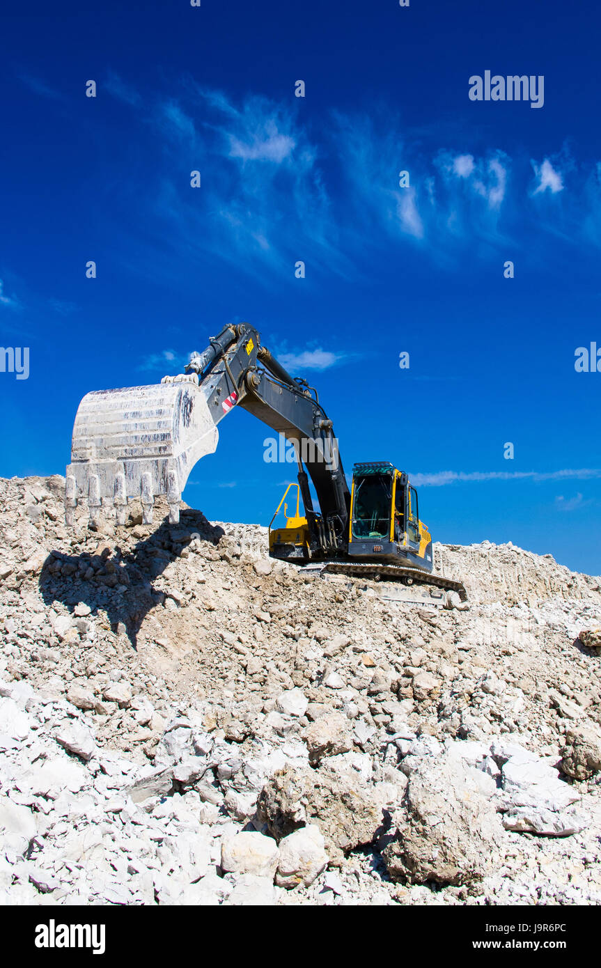 the excavator digging clay on blue sky background Stock Photo - Alamy