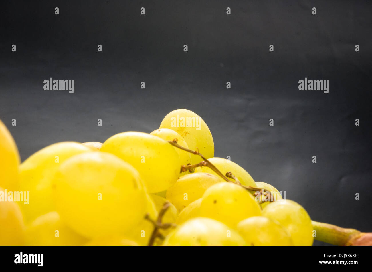 Large grapes cluster amber color on black background Stock Photo - Alamy