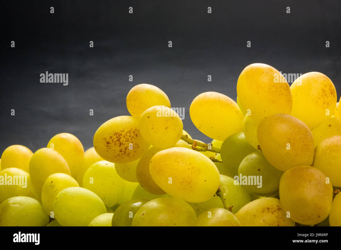 Large grapes cluster amber color on black background Stock Photo - Alamy