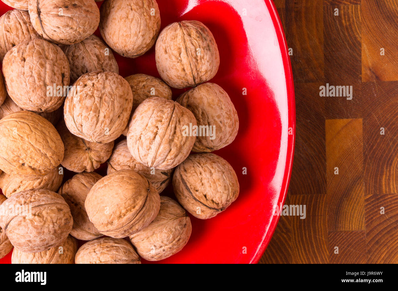 walnuts in red plate on wooden background Stock Photo - Alamy