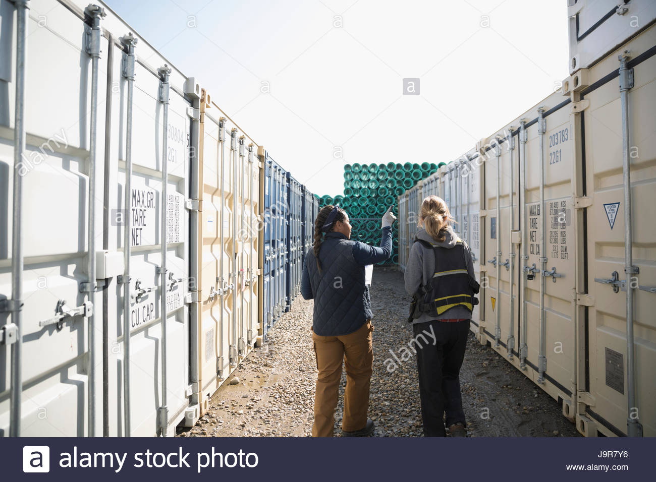 Female workers checking shipping containers in industrial container ...