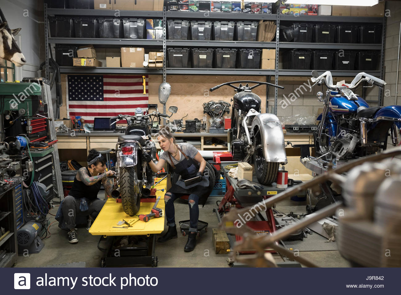 Female motorcycle mechanics fixing motorcycle in auto repair shop Stock ...