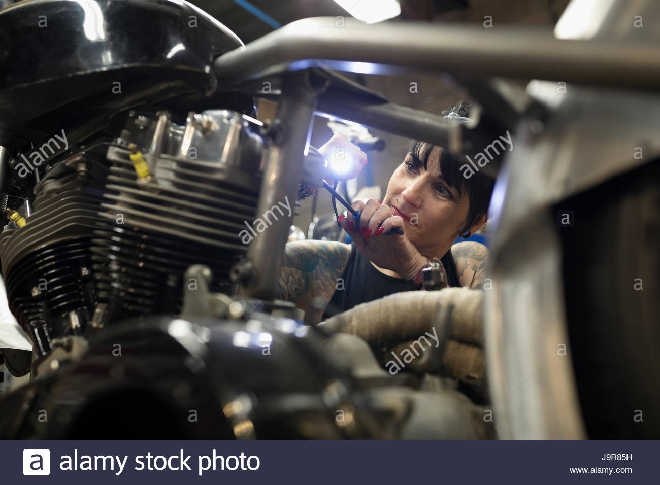 Female motorcycle mechanic fixing engine in auto repair shop Stock ...