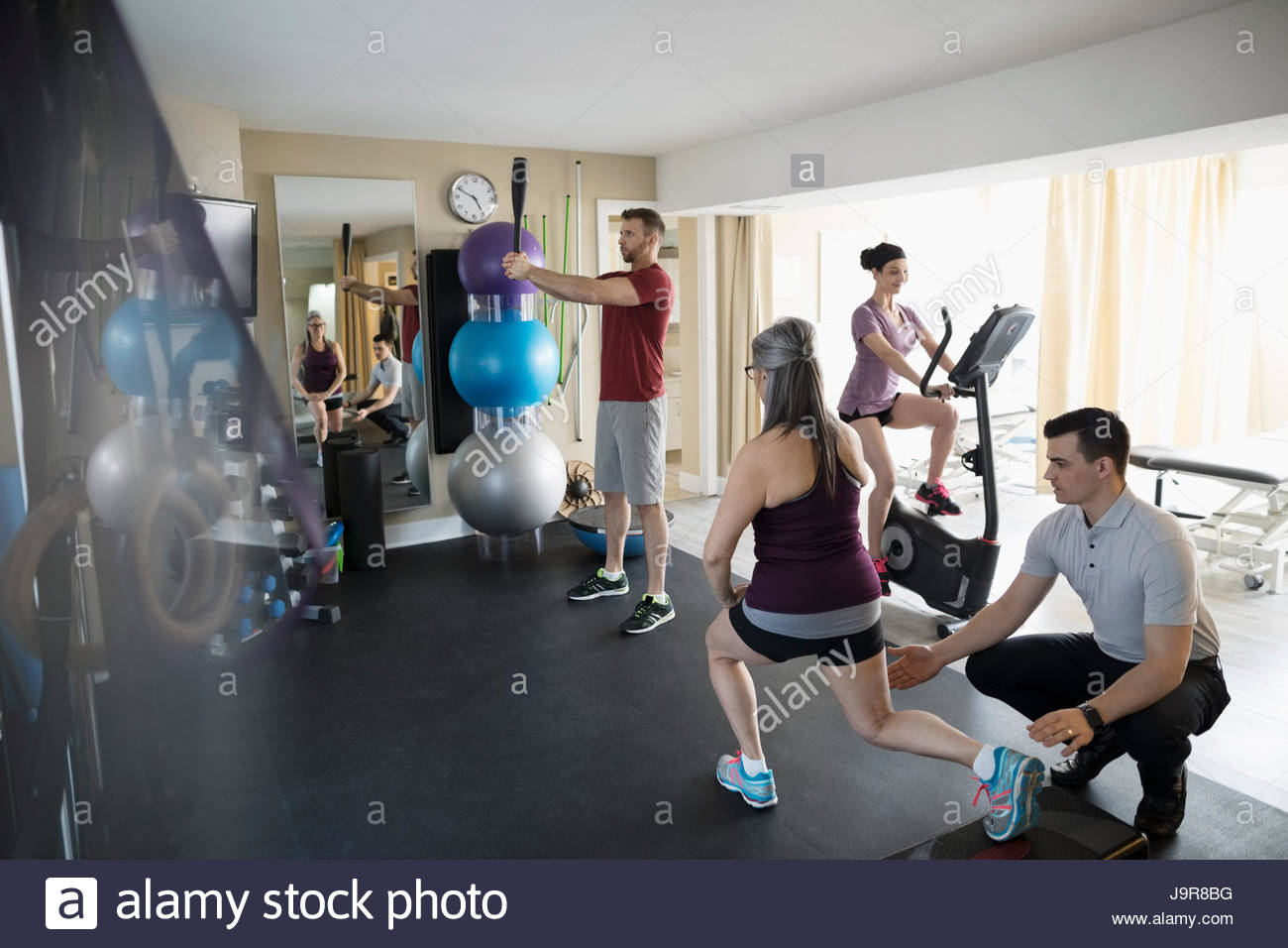 Male physiotherapist guiding clients stretching and exercising in ...