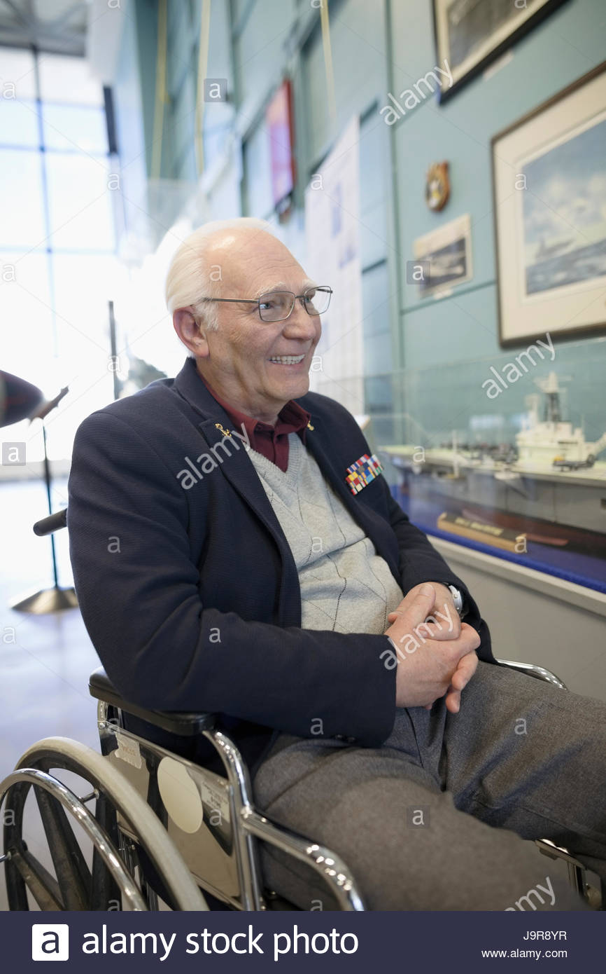 Portrait smiling senior male war veteran in wheelchair in war museum ...