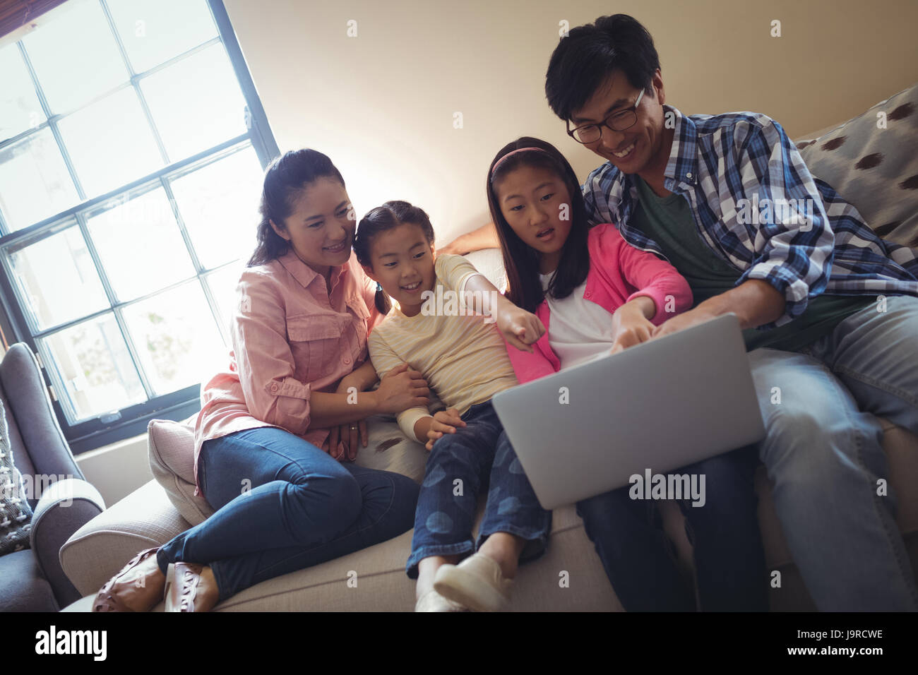 Family using laptop together in living room at home Stock Photo - Alamy