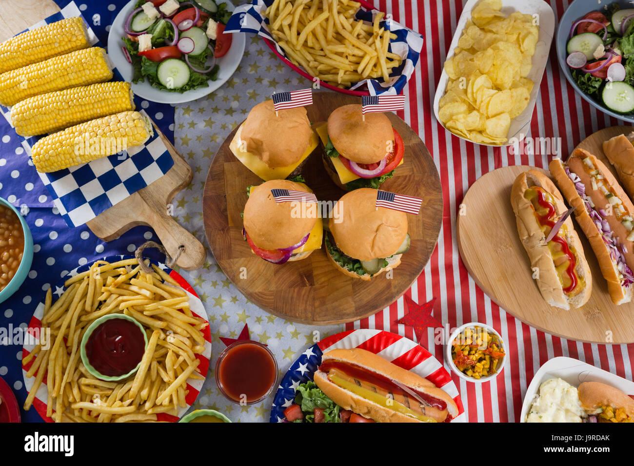Close-up of hot dogs and burgers on wooden table with 4th july theme ...