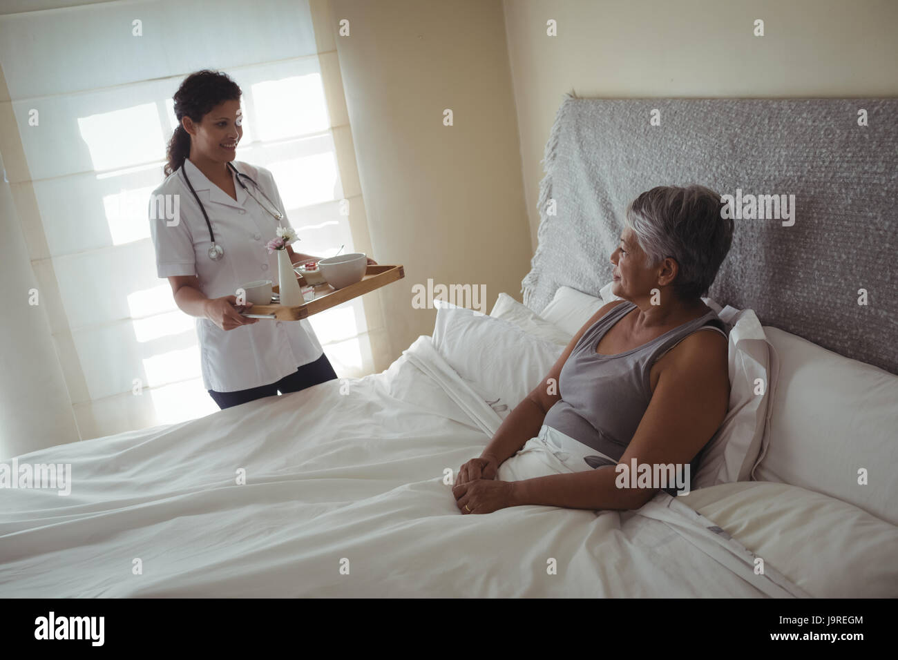 Female doctor serving breakfast to senior woman at home Stock Photo - Alamy