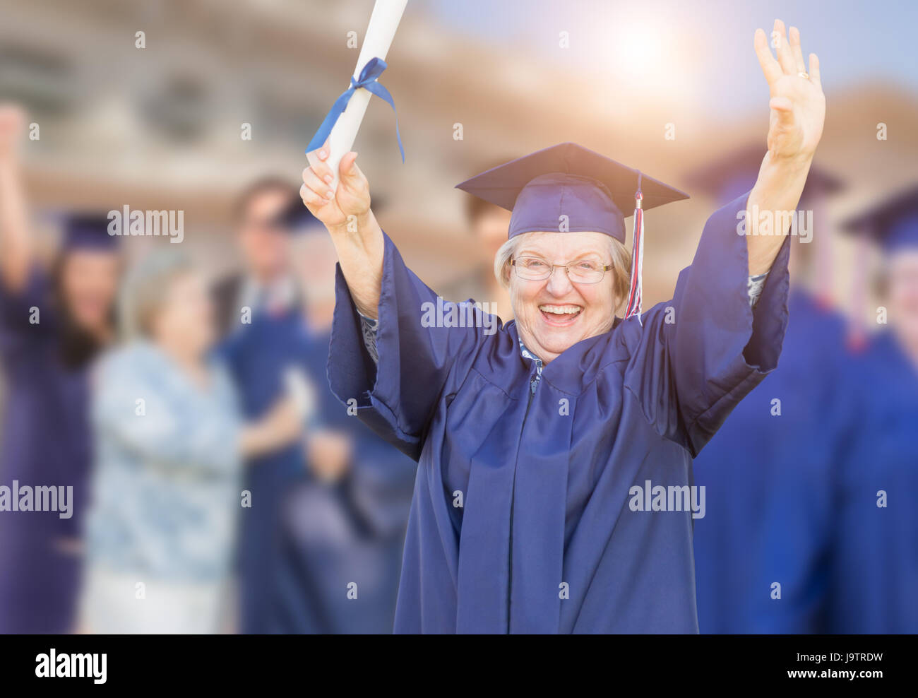 Happy Senior Adult Woman In Cap and Gown At Outdoor Graduation Ceremony ...