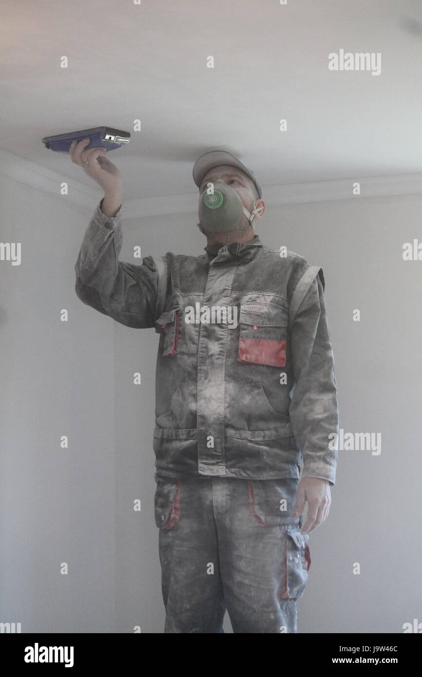 young man in respirator in uniform covered white dust made repair in ...