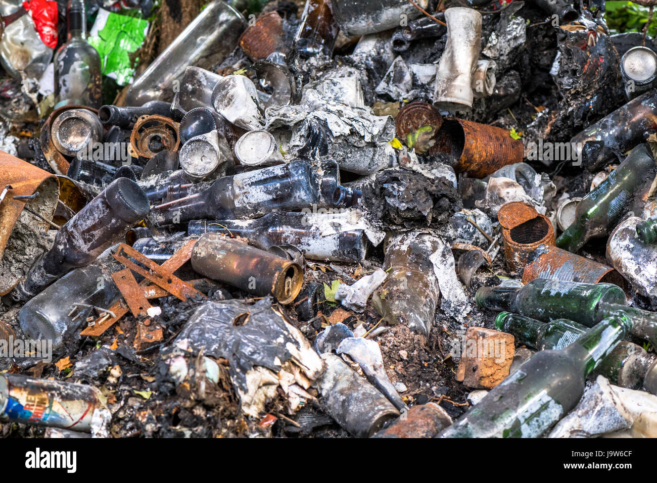 Discarded glass bottles and beer cans burnt in a fly tip Stock Photo ...