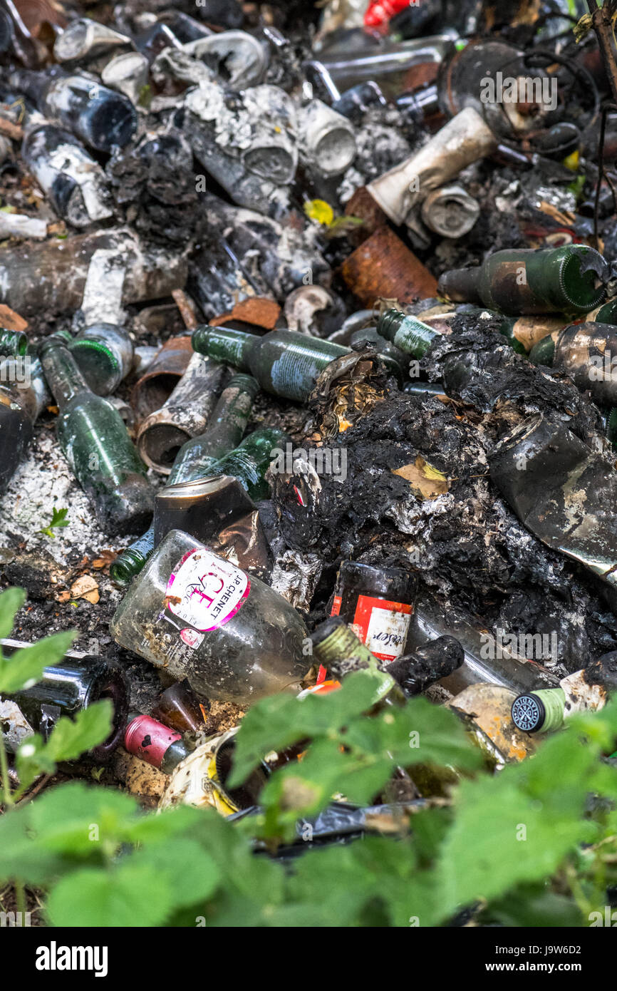 Discarded glass bottles and beer cans burnt in a fly tip Stock Photo ...