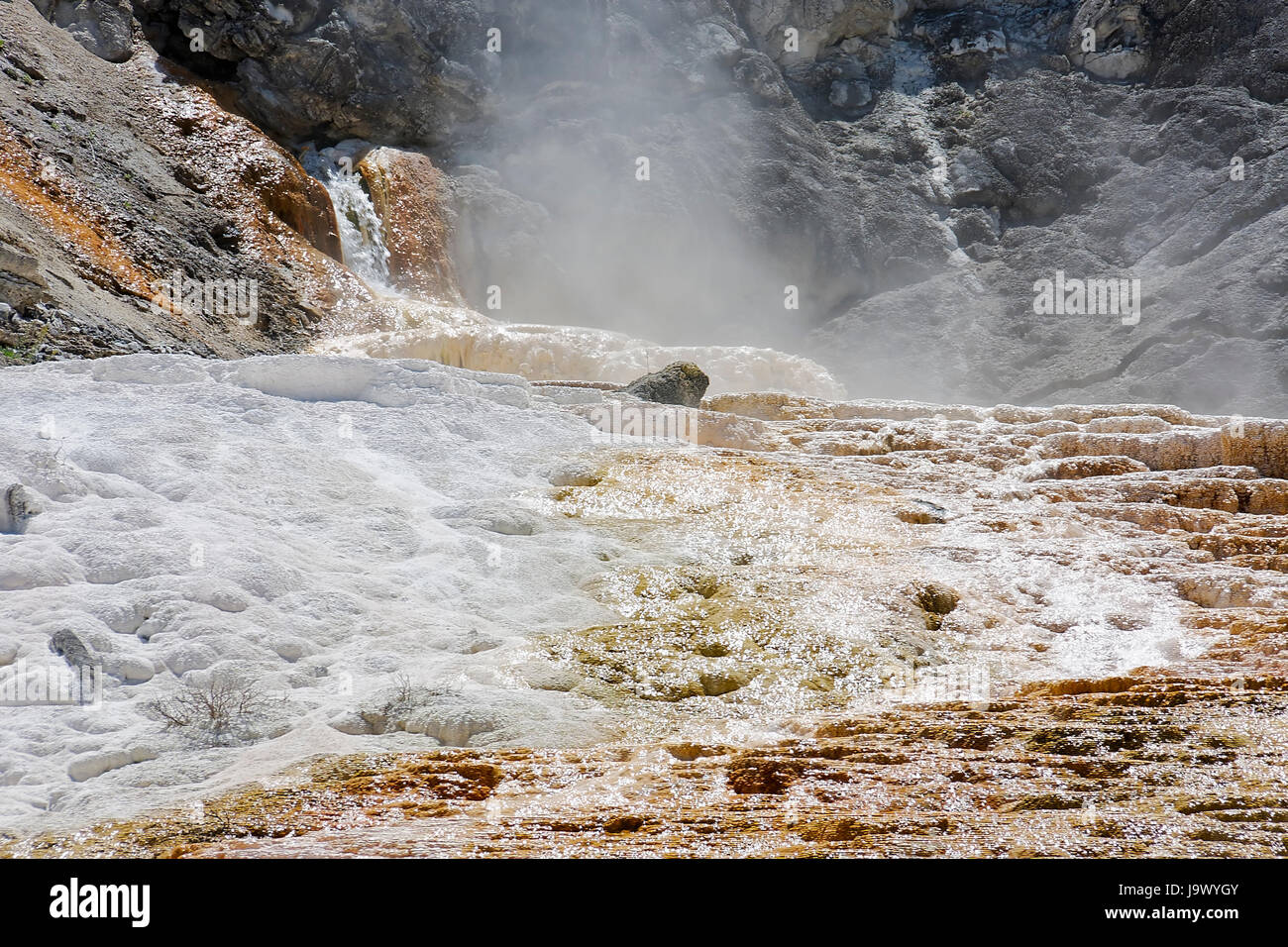 Water from a hot spring runs from a crack in the rocks depositing a bed ...