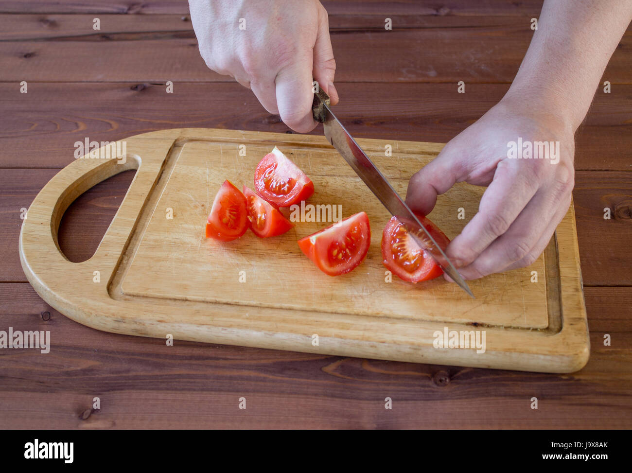 Cut the tomatoes with a kitchen knife on the cutting board. Wooden ...