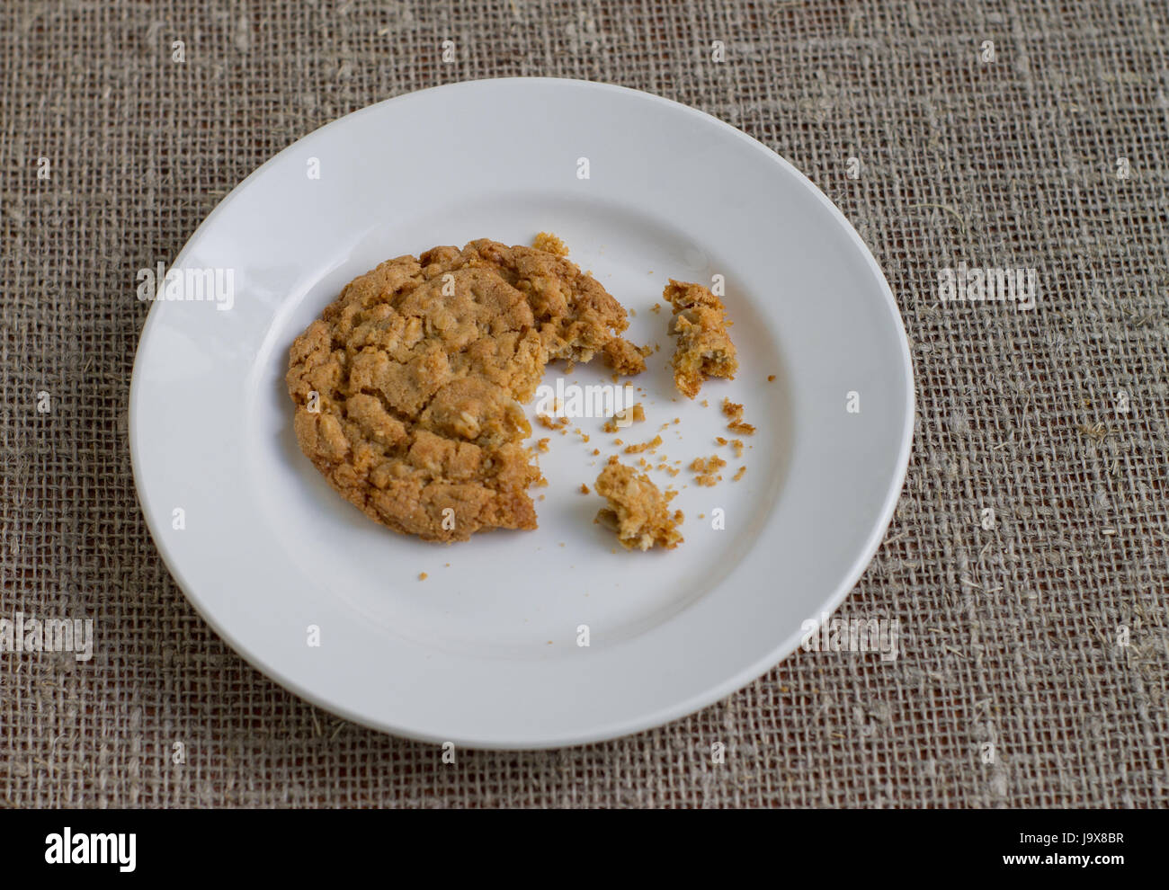A bitten cookie on a white plate. Background burlap Stock Photo - Alamy