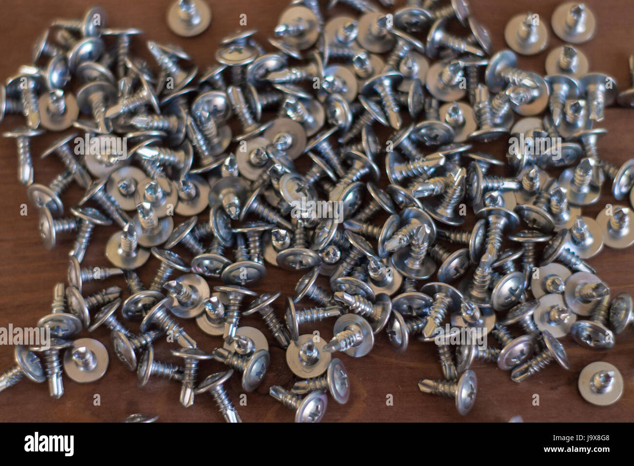 Self-tapping screws on a wooden background Stock Photo - Alamy