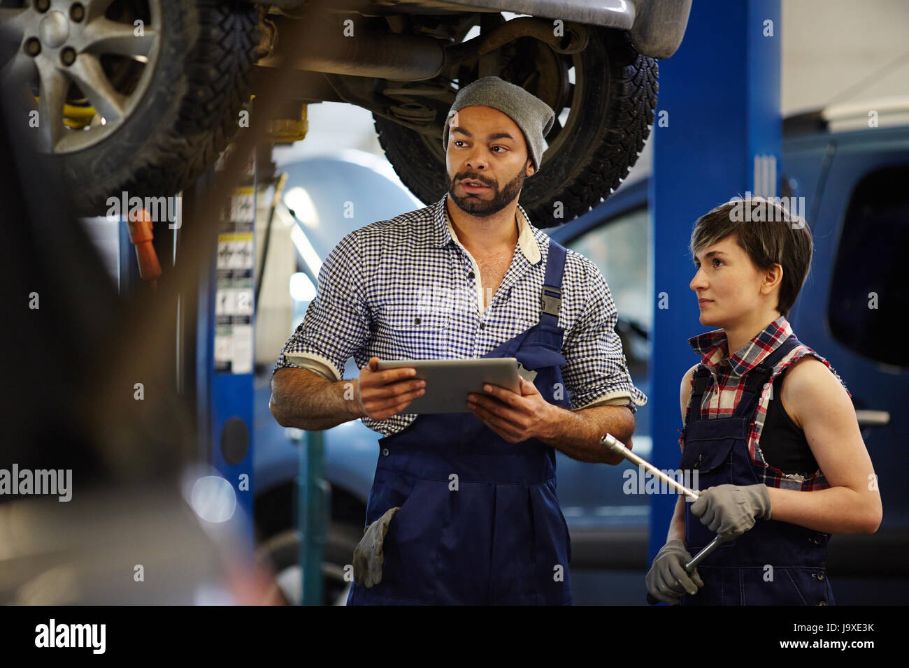 Repair mentor consulting his trainee in garage Stock Photo - Alamy