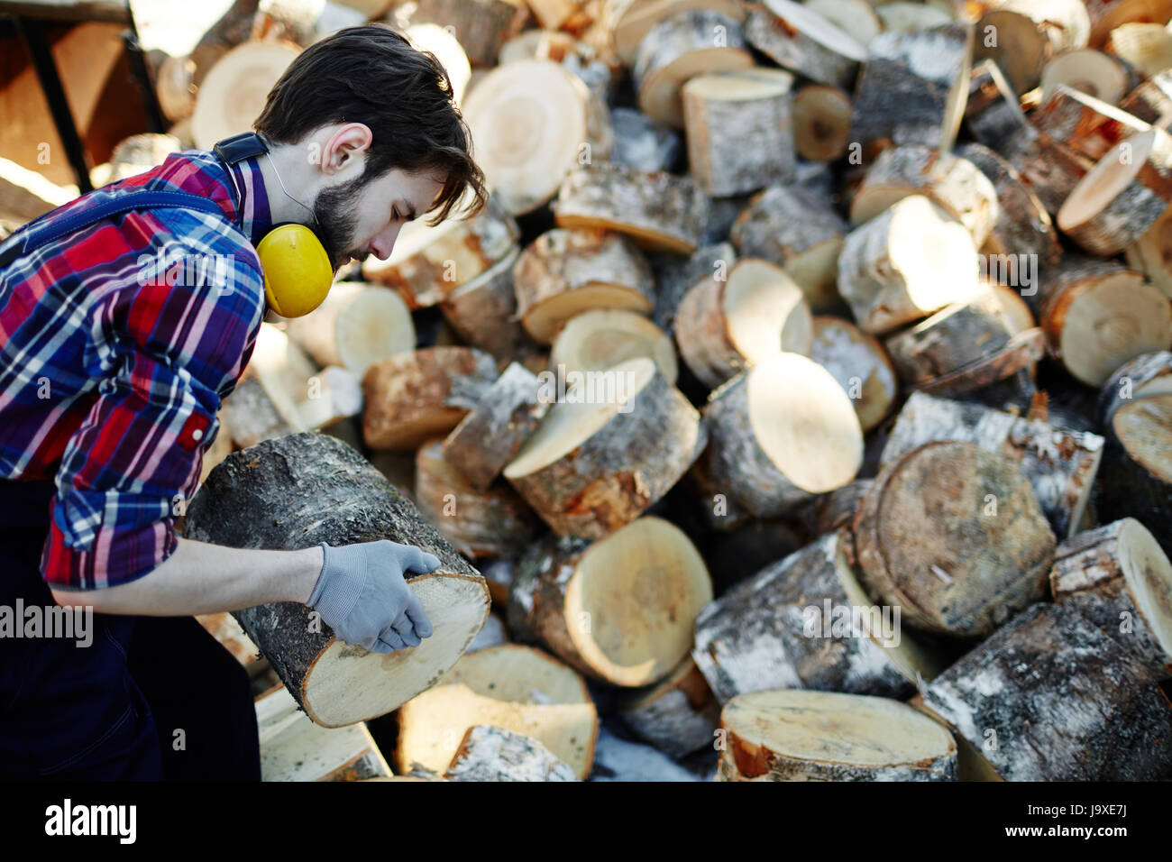 Young worker carrying log while working at lumberyard Stock Photo - Alamy