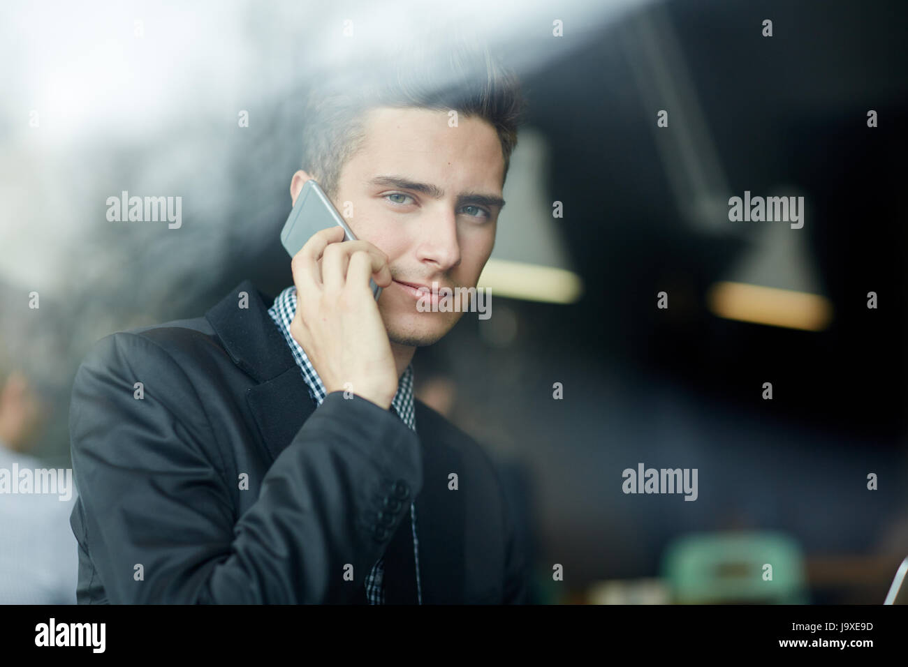 Young agent talking by smartphone and looking at camera Stock Photo - Alamy