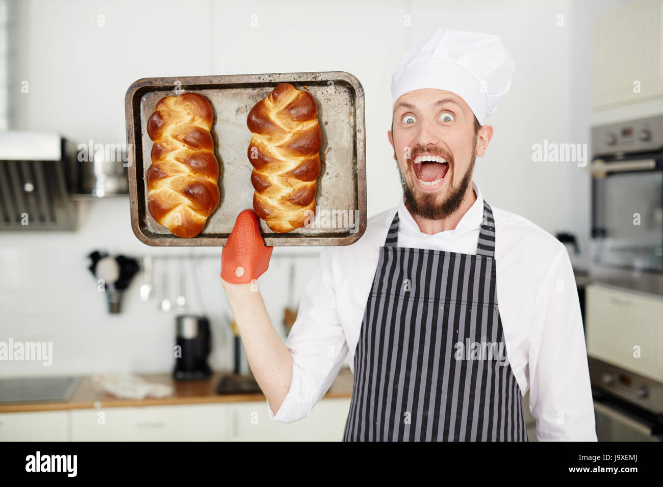 Baker holding hot tray with fresh-made bread Stock Photo - Alamy