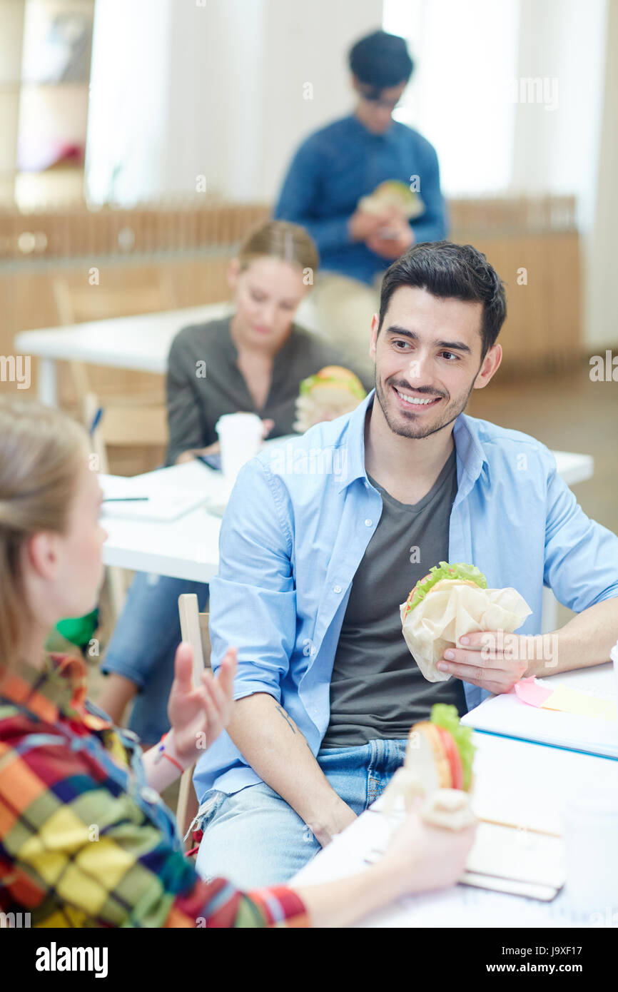 Friendly groupmates with sandwiches discussing news at lunch break ...