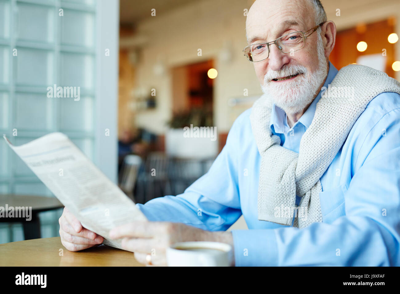 Mature man with newspaper looking at camera Stock Photo - Alamy